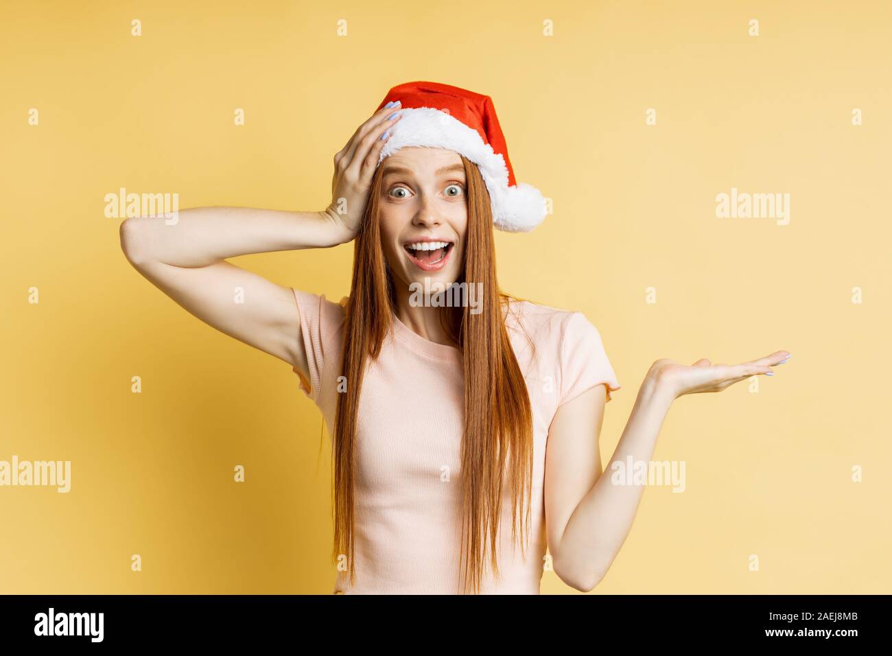 Stunned caucasian ginger girl in Santa hat and cream color t shirt ...