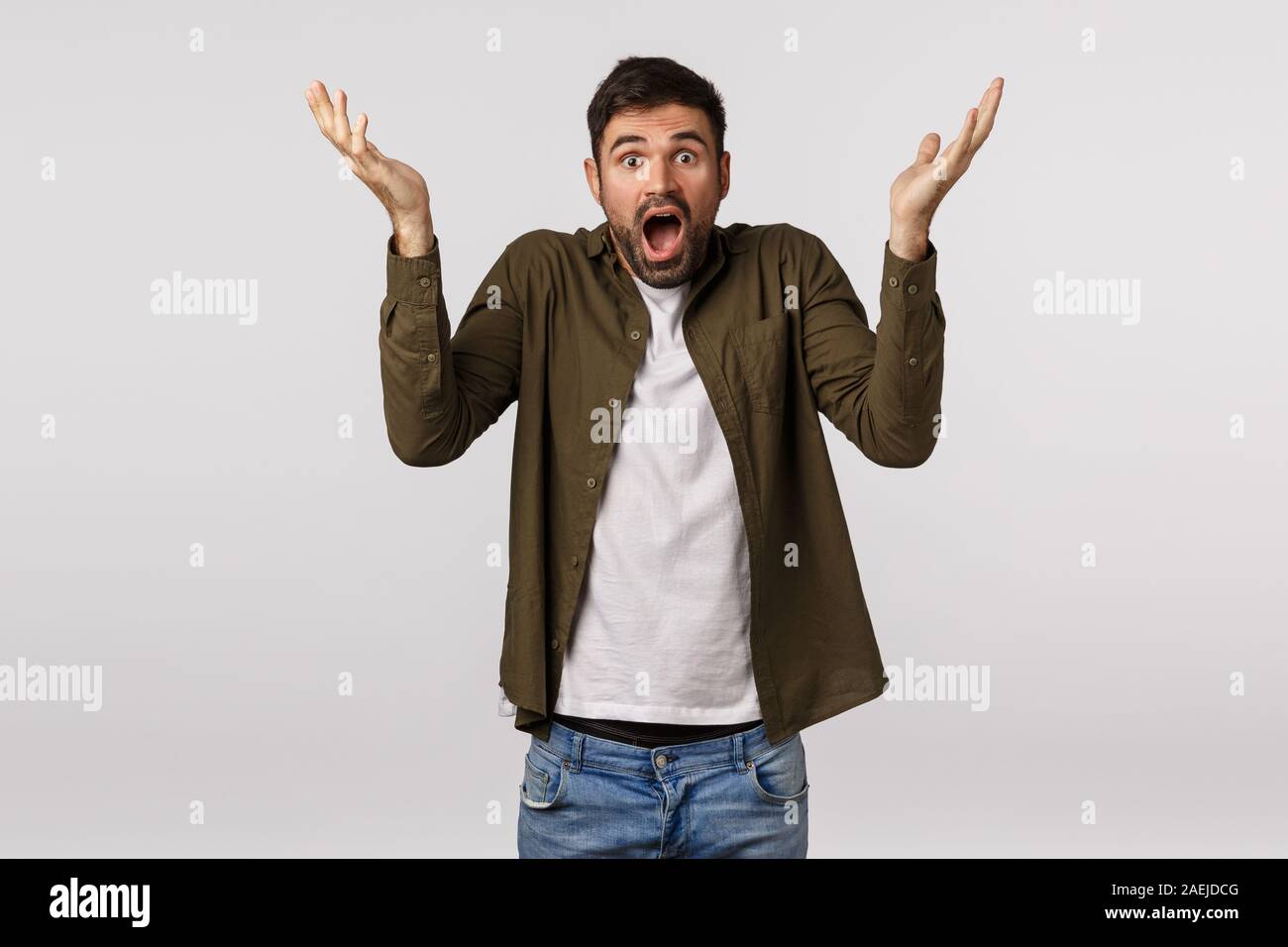 Shocked and embarrassed, bearded man panicking, raise hands up sideways ...