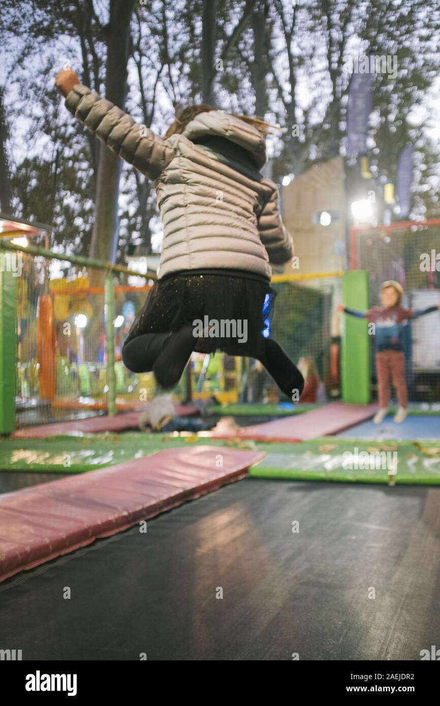 Girl with grey jacket jumping and playing on a stretch bed on a ...