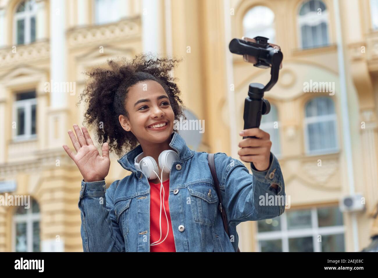Outdoors Leisure. Young girl blogger with headphones walking holding ...