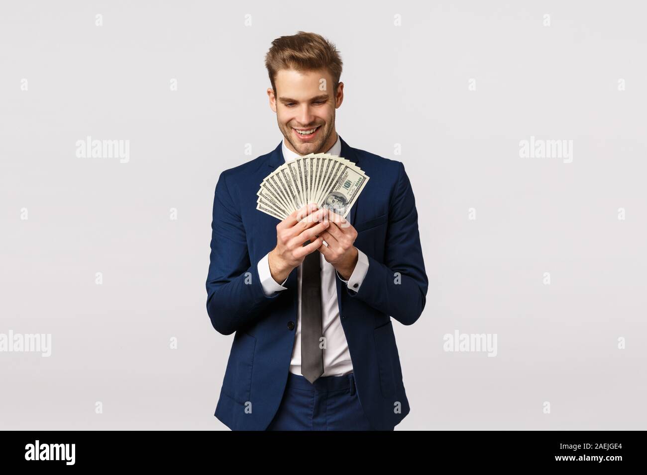 Happy and excited, good-looking businessman in classic suit, counting ...