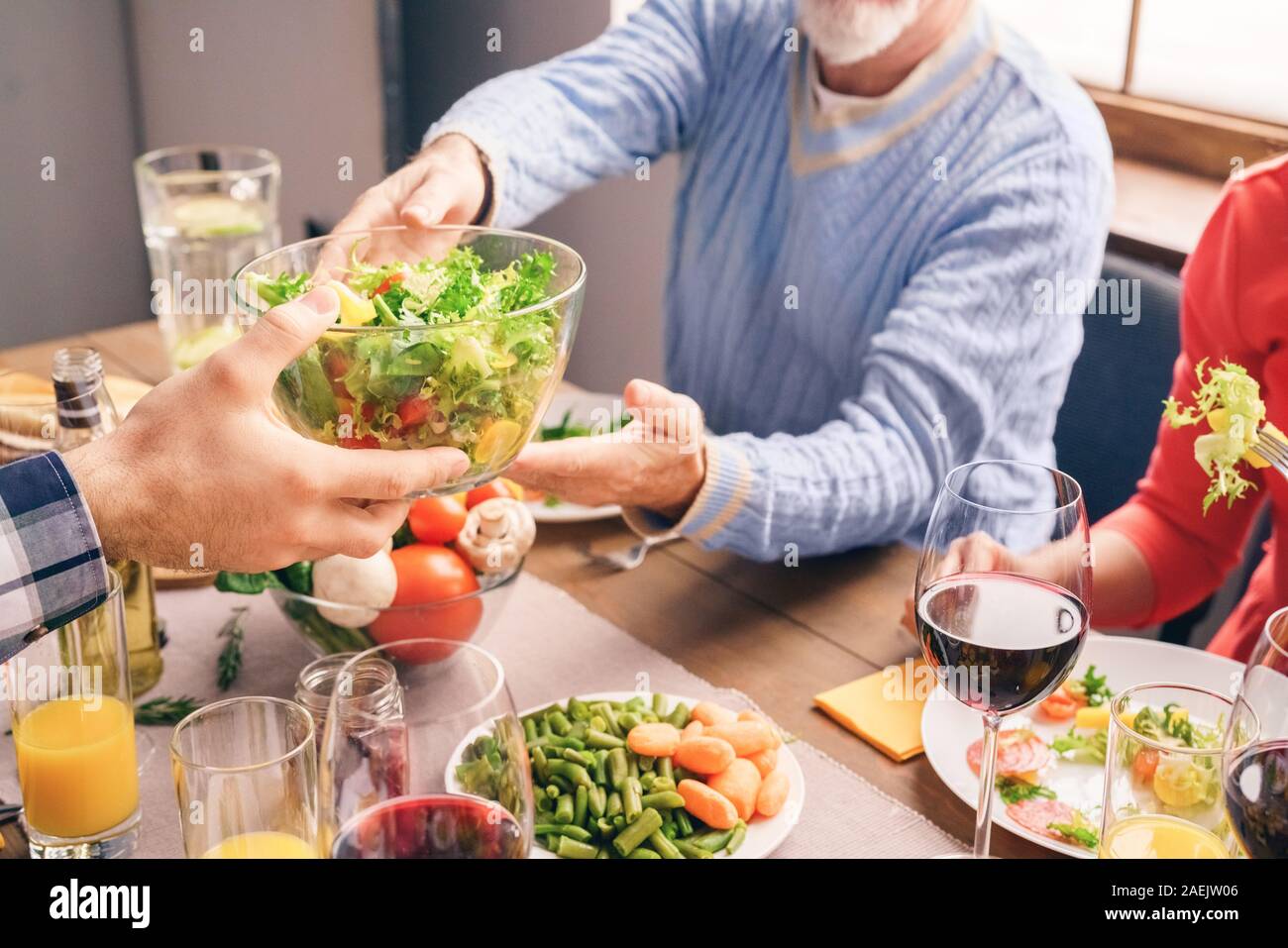 Family at the festive table. Old man passes the salad Stock Photo - Alamy