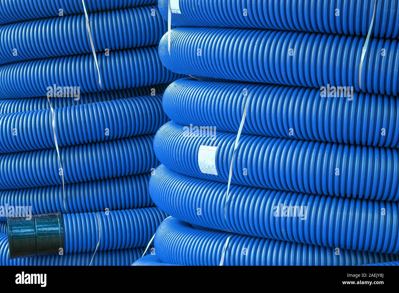 Coils of new red plastic pipe with rain drops. Red plastic tubing for ...