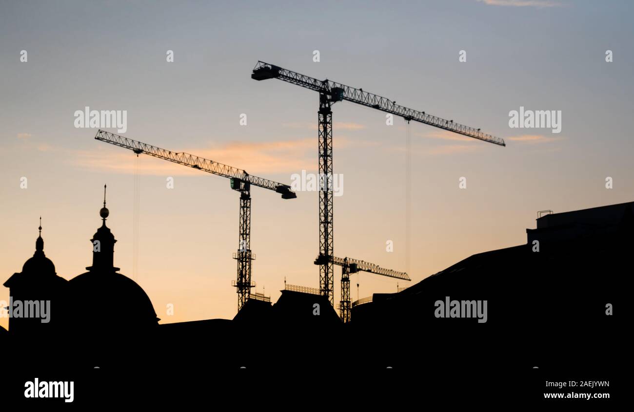 Tower cranes and unfinished building construction silhouette against ...