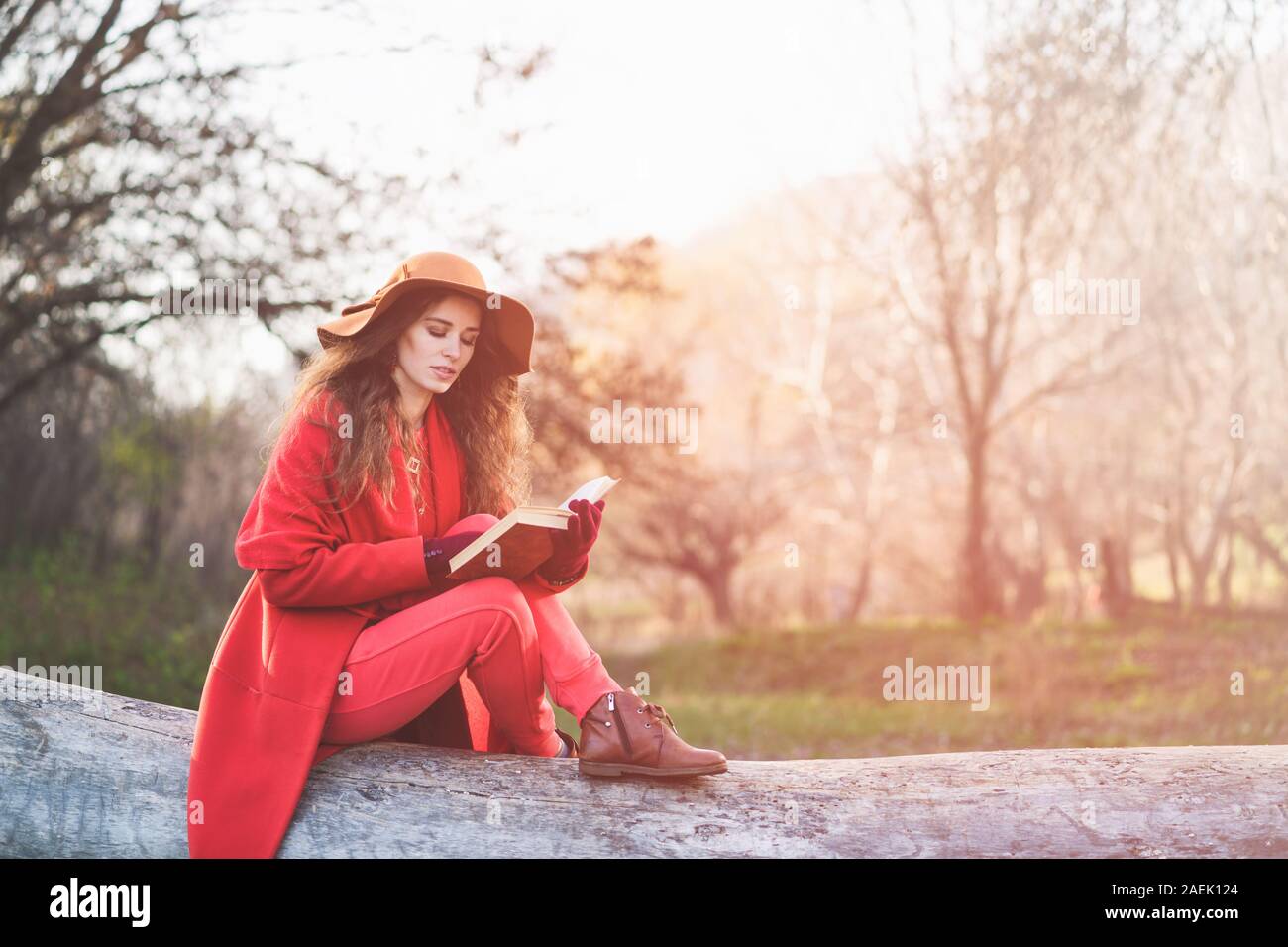 Girl sit on log and read book Stock Photo - Alamy