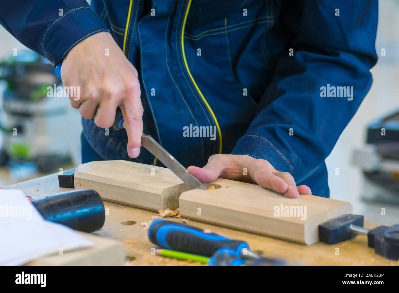 Carpenter using chisel to carve wood on rough workbench at workshop ...