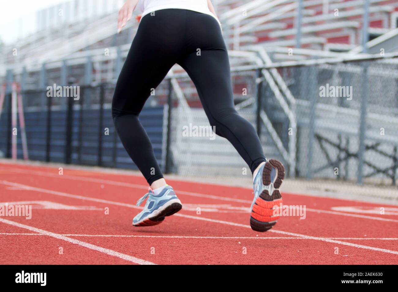 A female high school track runner starts her sprint down the track ...