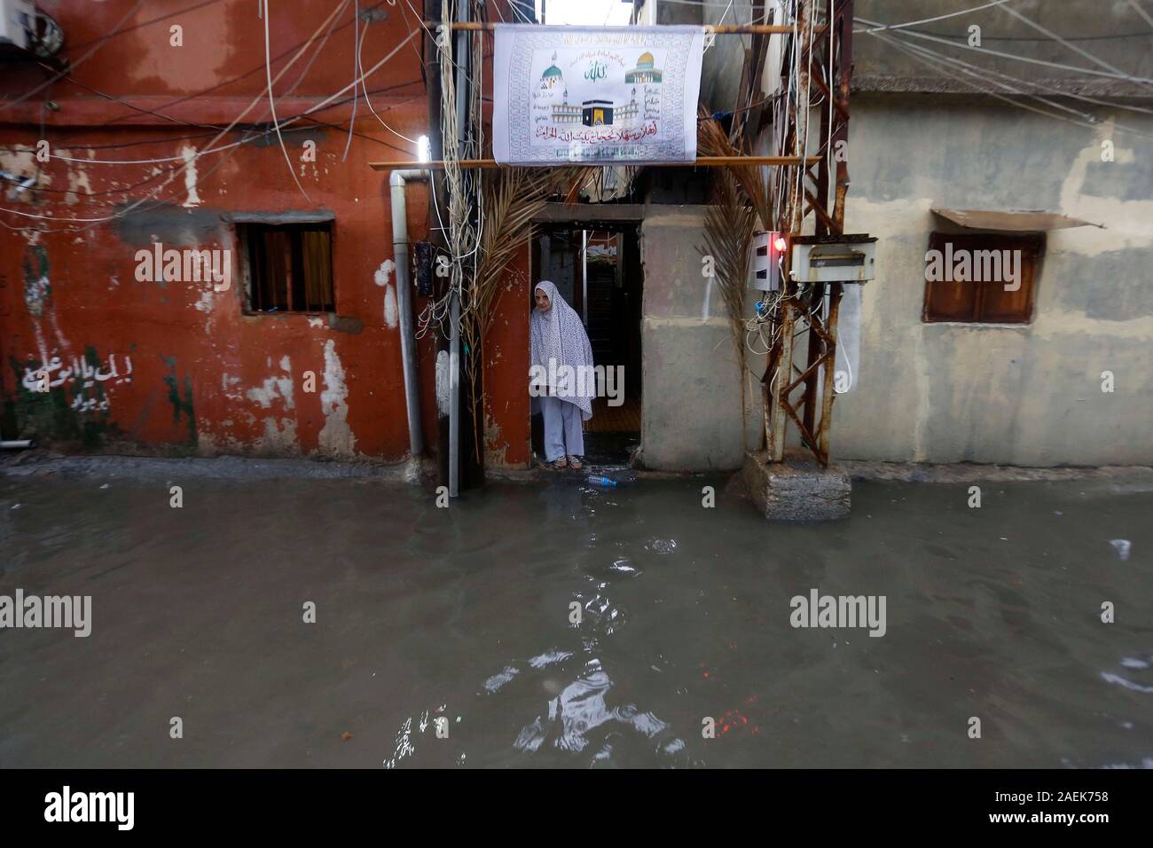 Beirut, Lebanon. 9th Dec, 2019. A woman stands at the door on a flooded ...