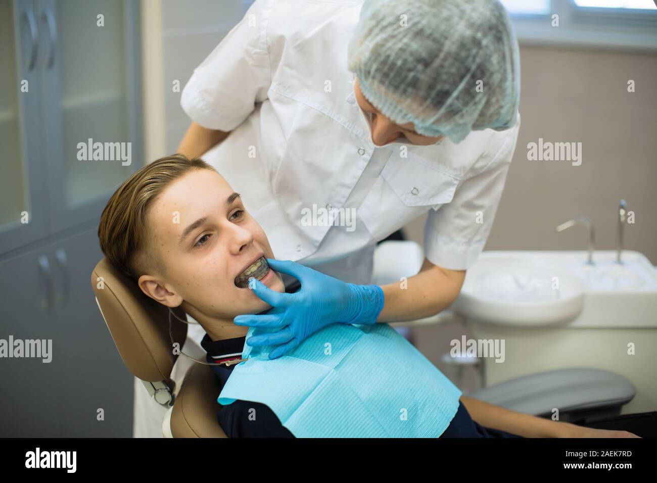 Woman dentist puts on a guy patient a mouth guard (a removable ...