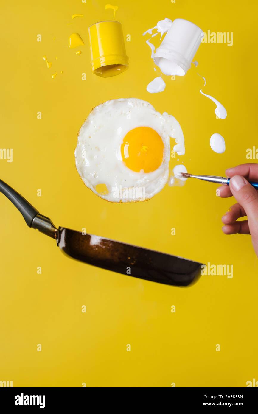 A fried egg and a pan with cans of paint and a brush rise into the air ...