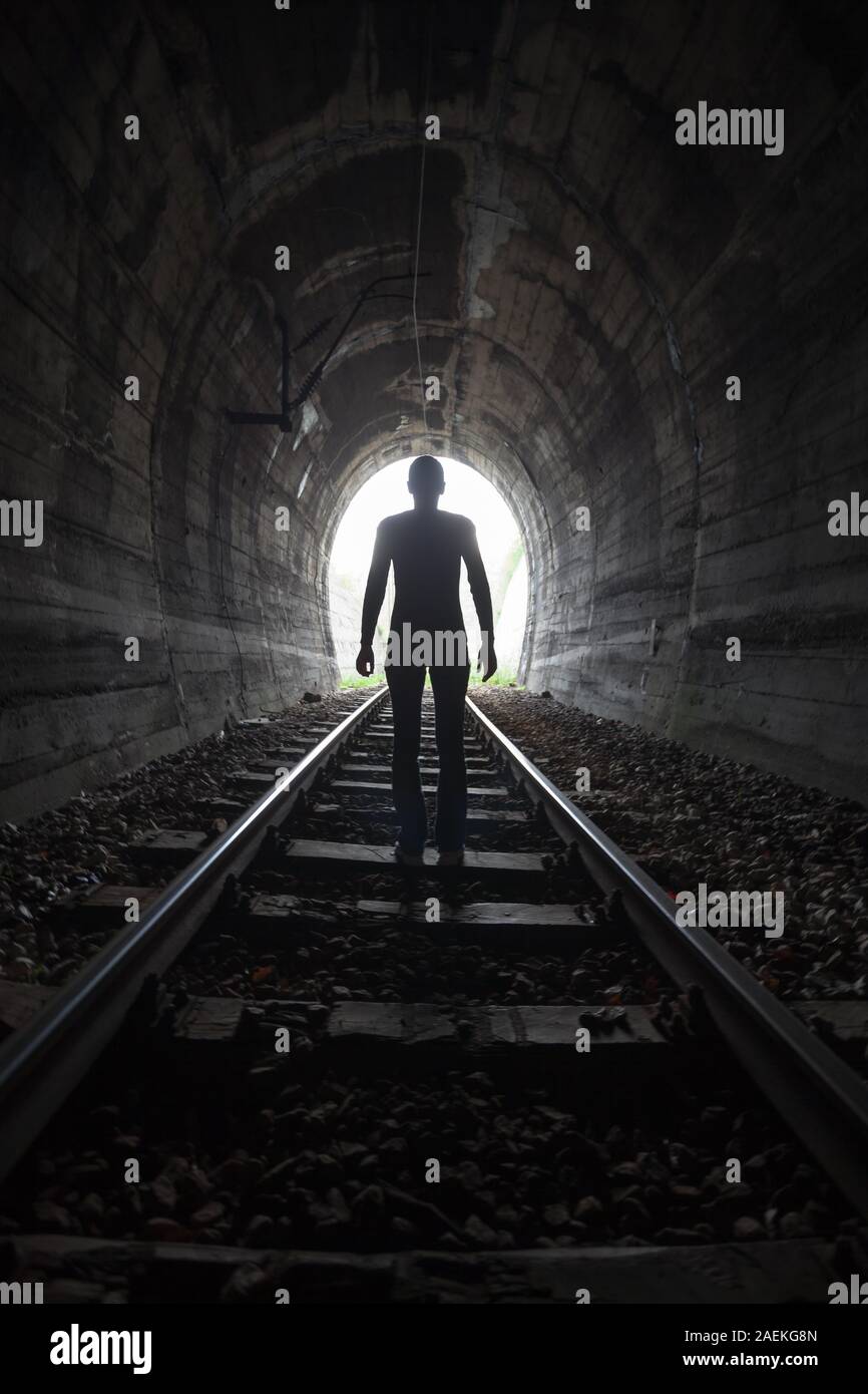 Man in a tunnel looking towards the light Stock Photo - Alamy
