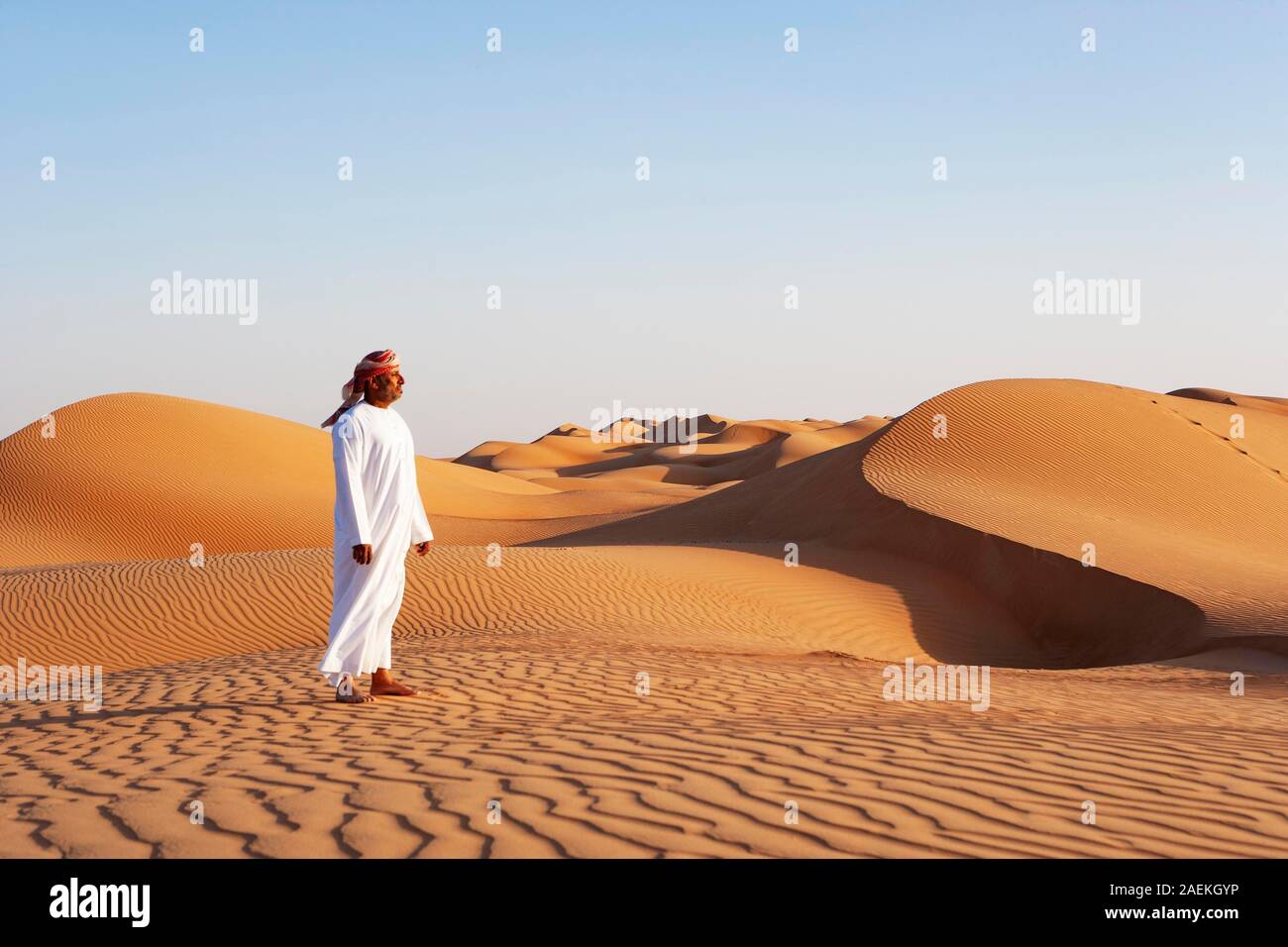 Bedouin in traditional clothing stands in the sand desert hi-res stock ...