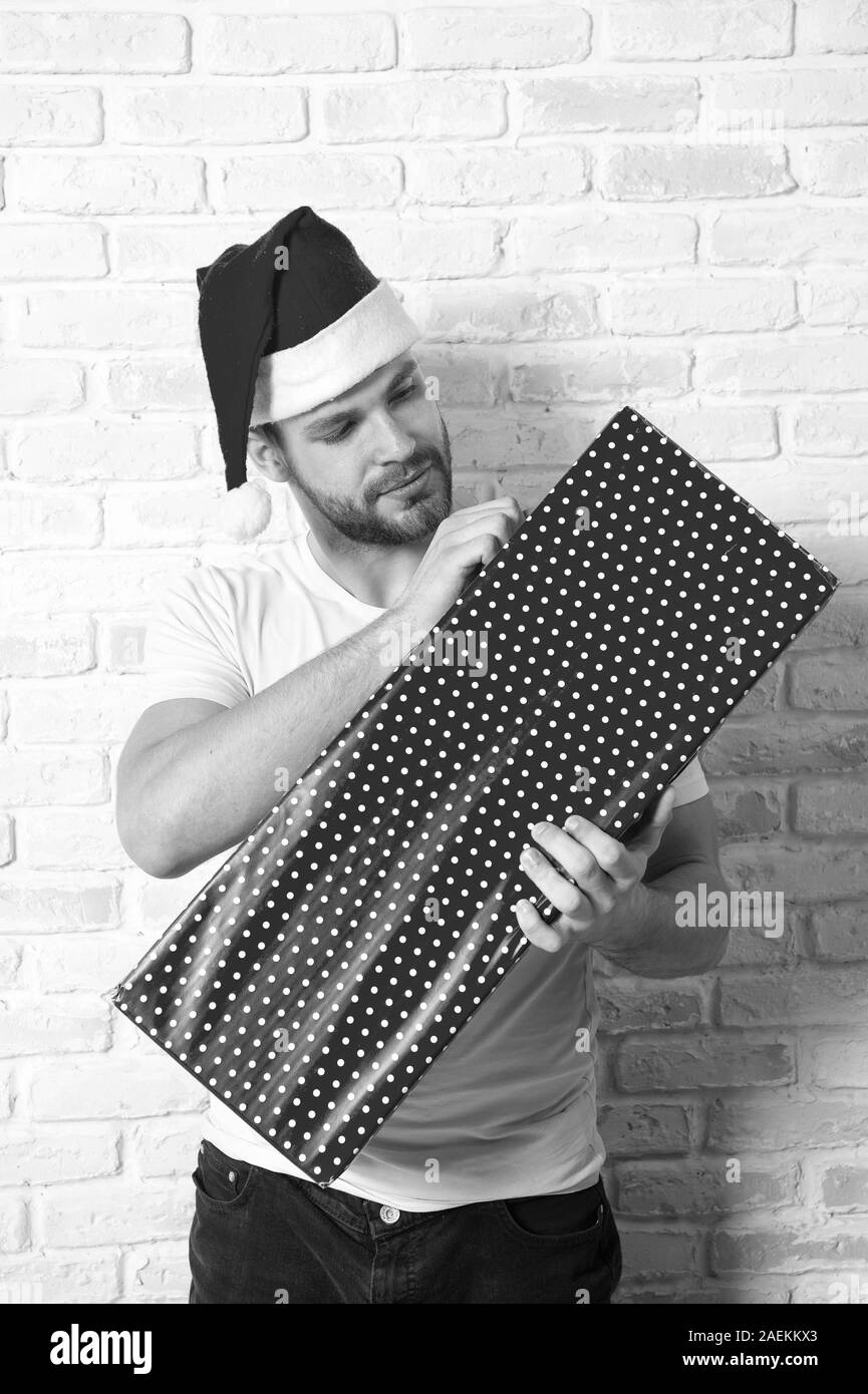 Man in santa hat open red christmas present box on white brick wall ...