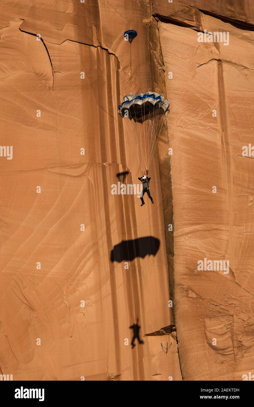 A BASE jumper descends in his parachute off the 400 foot vertical face ...