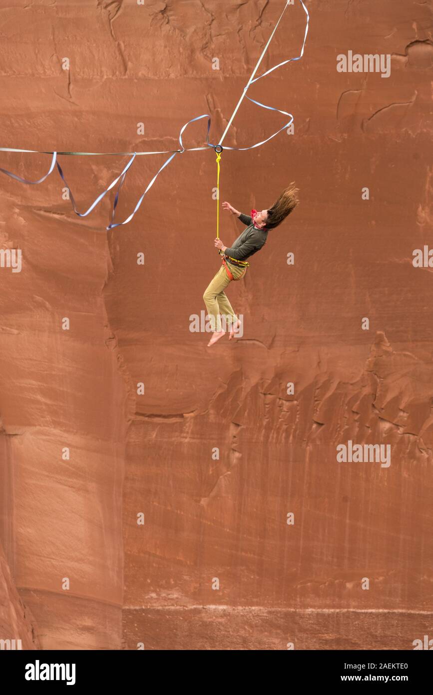 A young man loses his balance and falls while slacklining or highlining ...