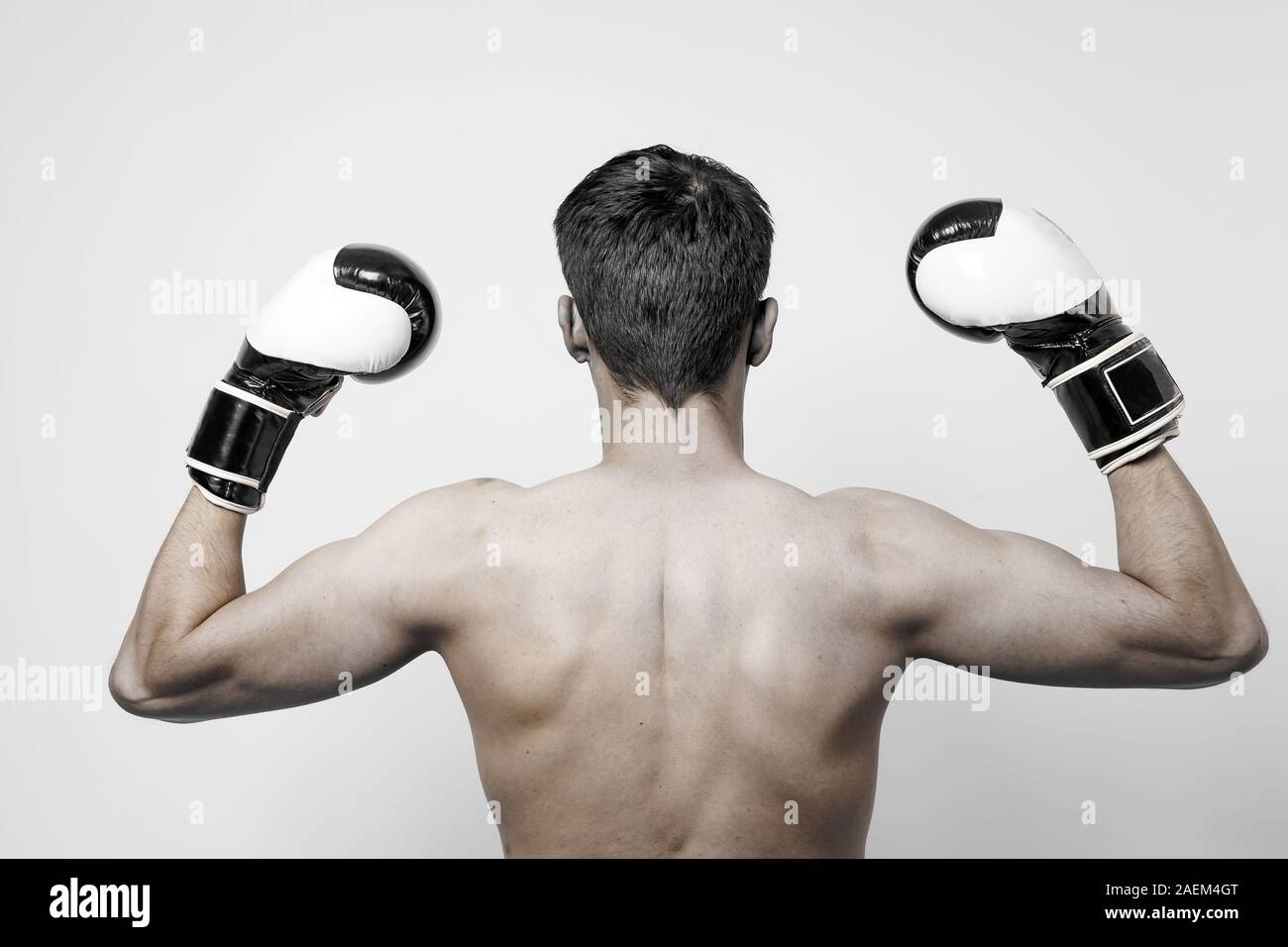 View from the back of a white brunet man raising his arms up in boxing ...
