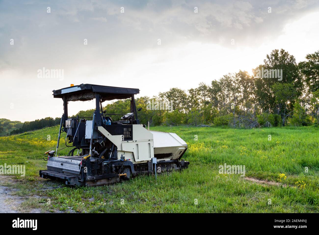 An paver machine for laying asphalt standing on the side of the track ...