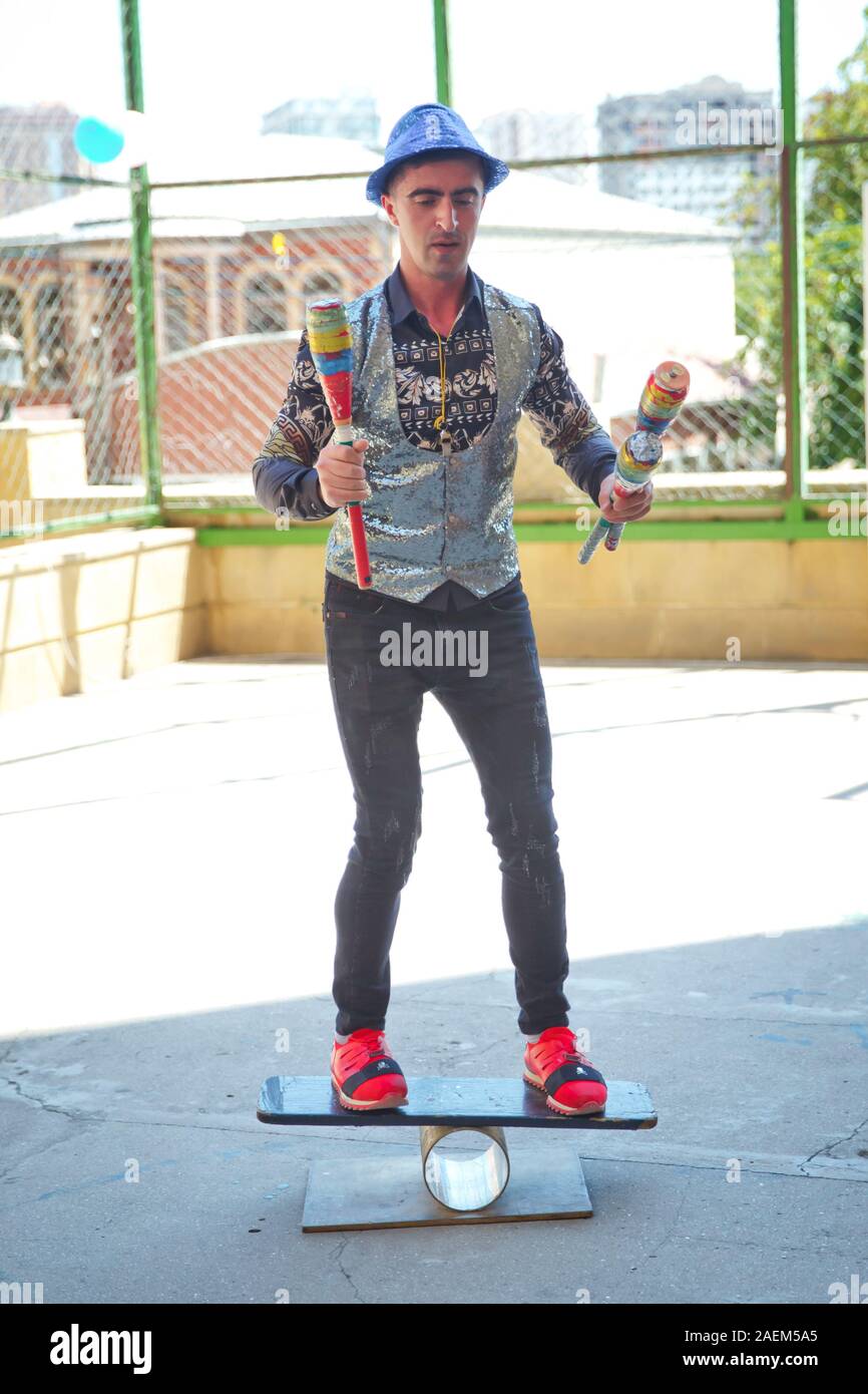Man standing on top of cylinders and juggling glass bottles, one bottle ...