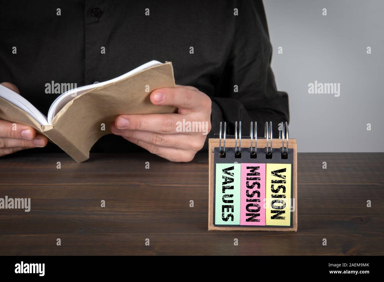Values, Mission and Vision concept. Man reading a book at a wooden ...