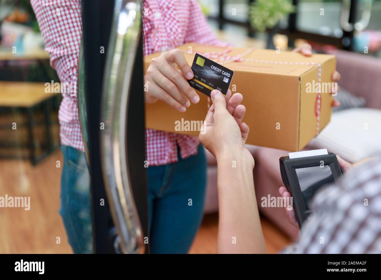Woman receiving parcel from delivery man at the door and payment by ...