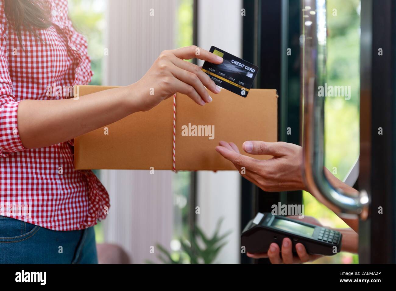 Woman receiving parcel from delivery man at the door and payment by ...