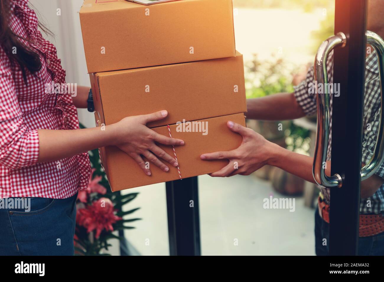 Woman receiving parcel from delivery man at the door Stock Photo - Alamy
