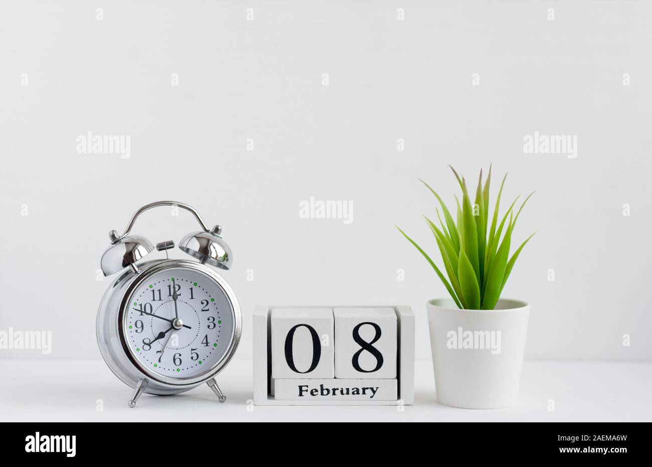 February 8 on a wooden calendar on a white background.Alarm clock and ...