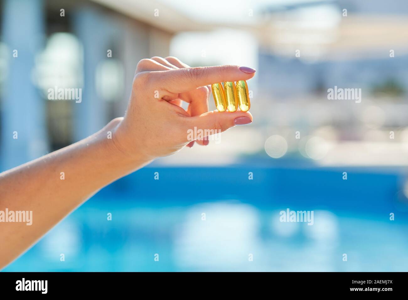 Sunny golden vitamin D oil capsules Omega-3 in woman hand Stock Photo ...