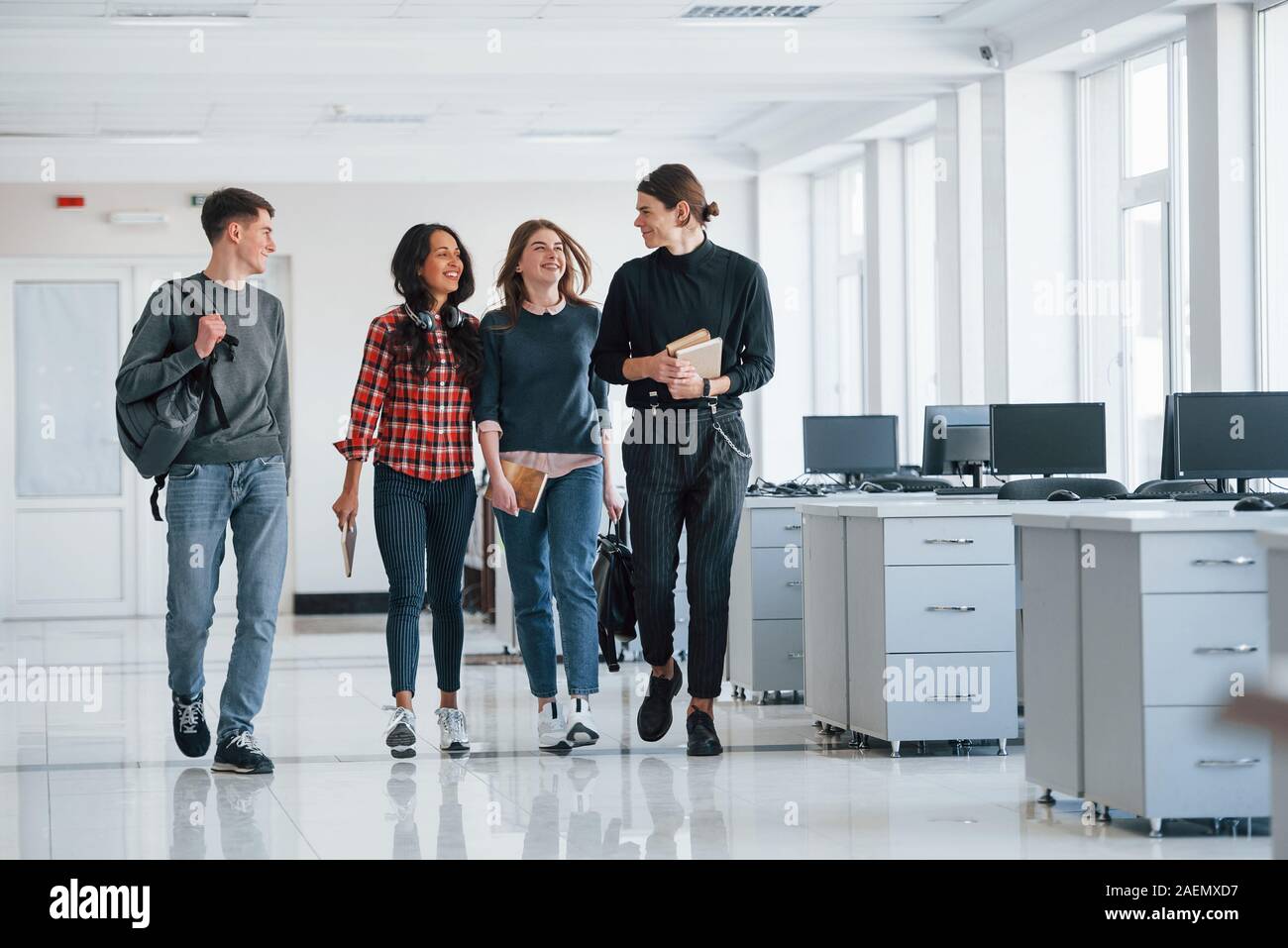 Time for a lunch. Group of young people walking in the office at their ...