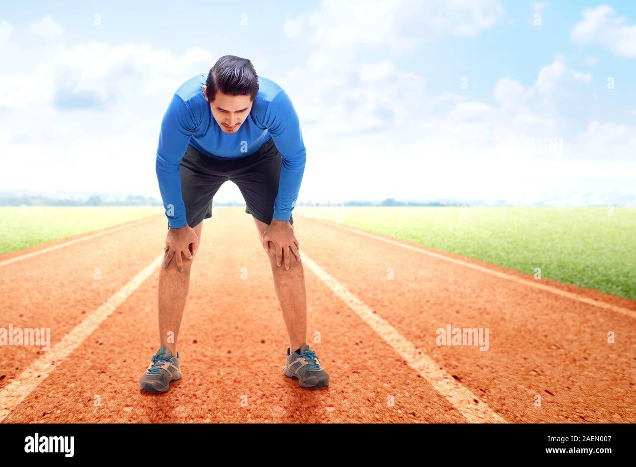 Asian runner man take a break after running on the running track with a ...