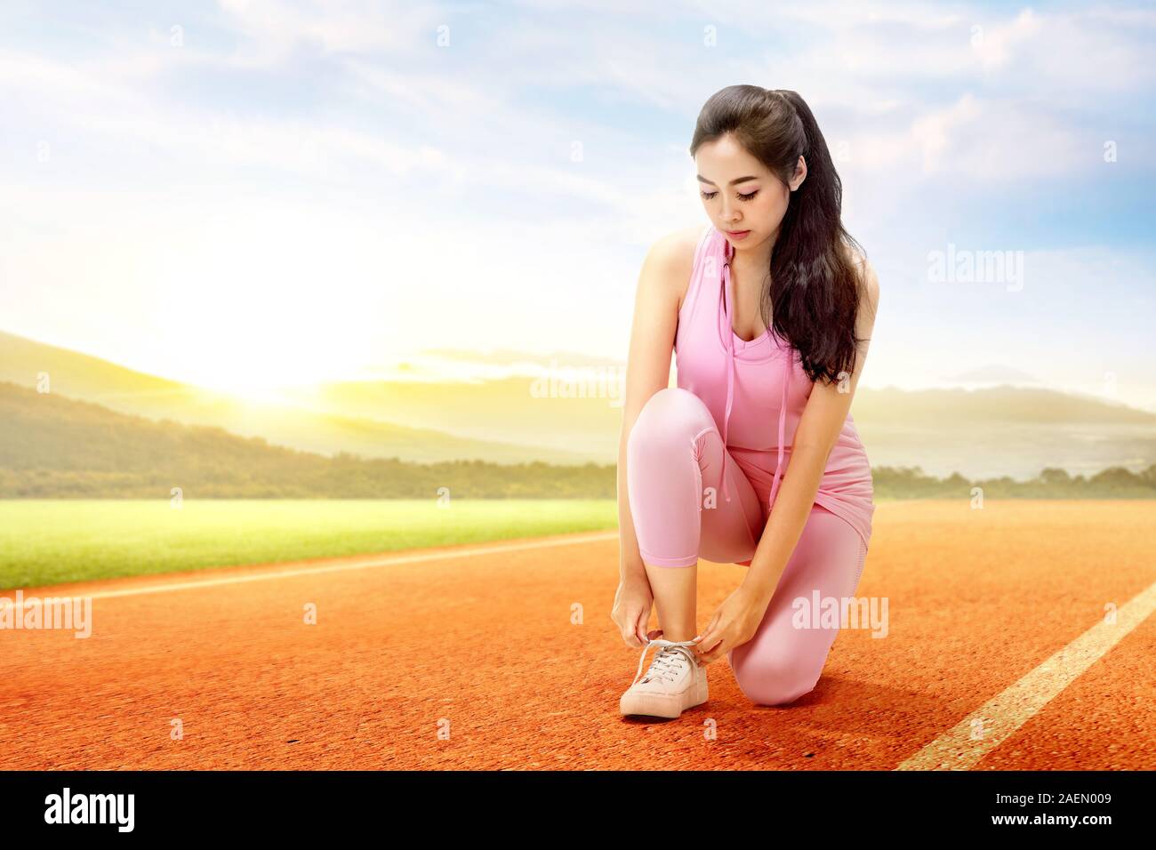 Asian runner woman tying running shoelaces on the running track with a ...