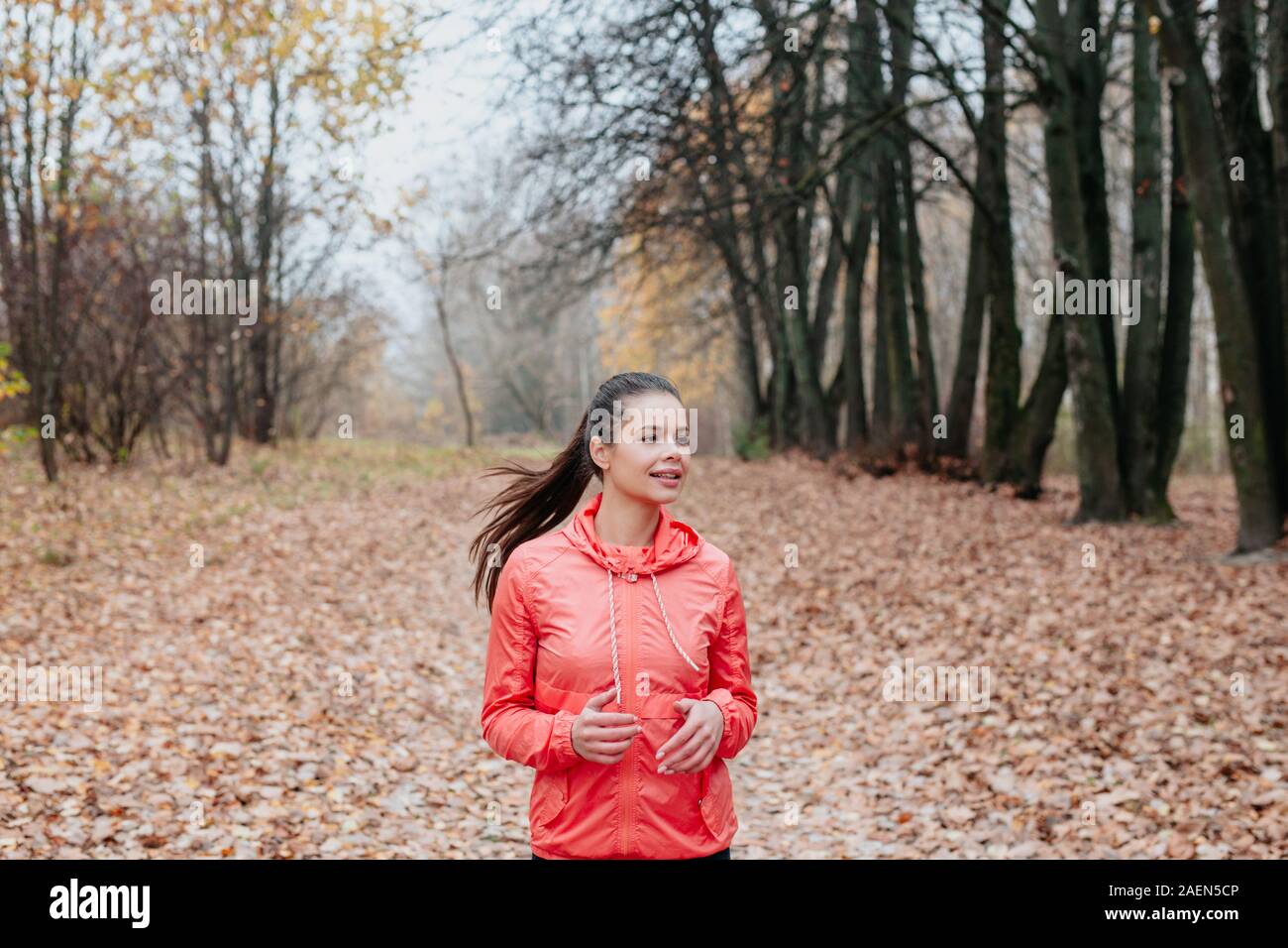 Young woman jogging in beautiful autumn city park in colorful fall ...
