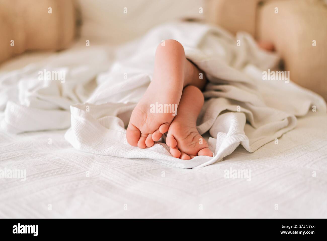 Feet of little sleeping child under white blanket on the bed Stock ...