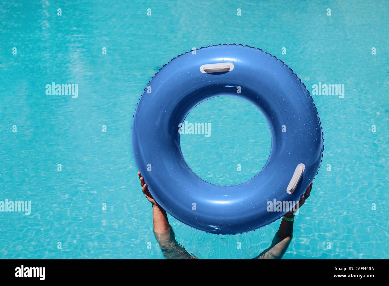 Hands holding rubber blue swimming ring above the water in swimming ...