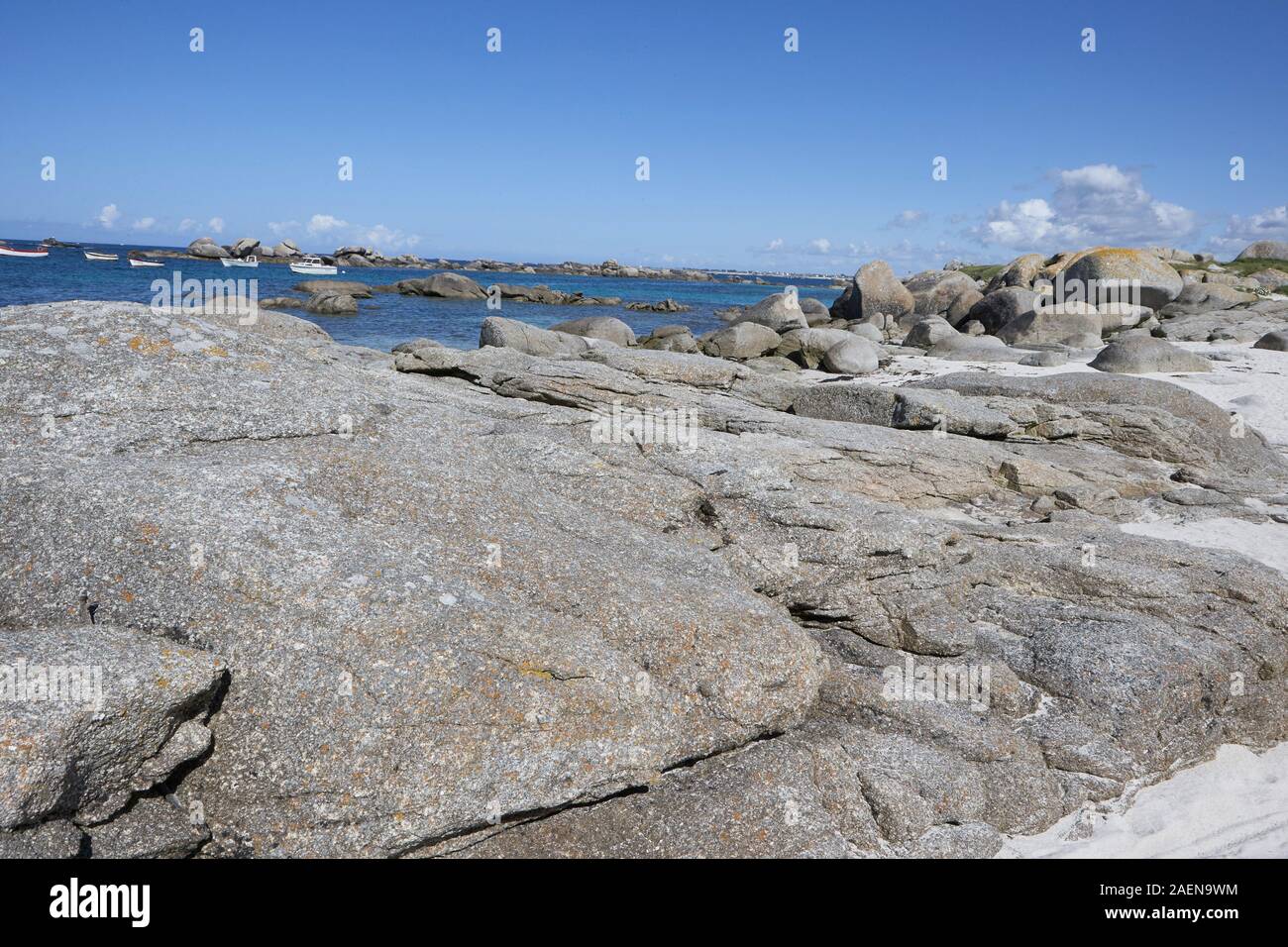 Coast with big rocks and blue water with small boats, summer holiday ...
