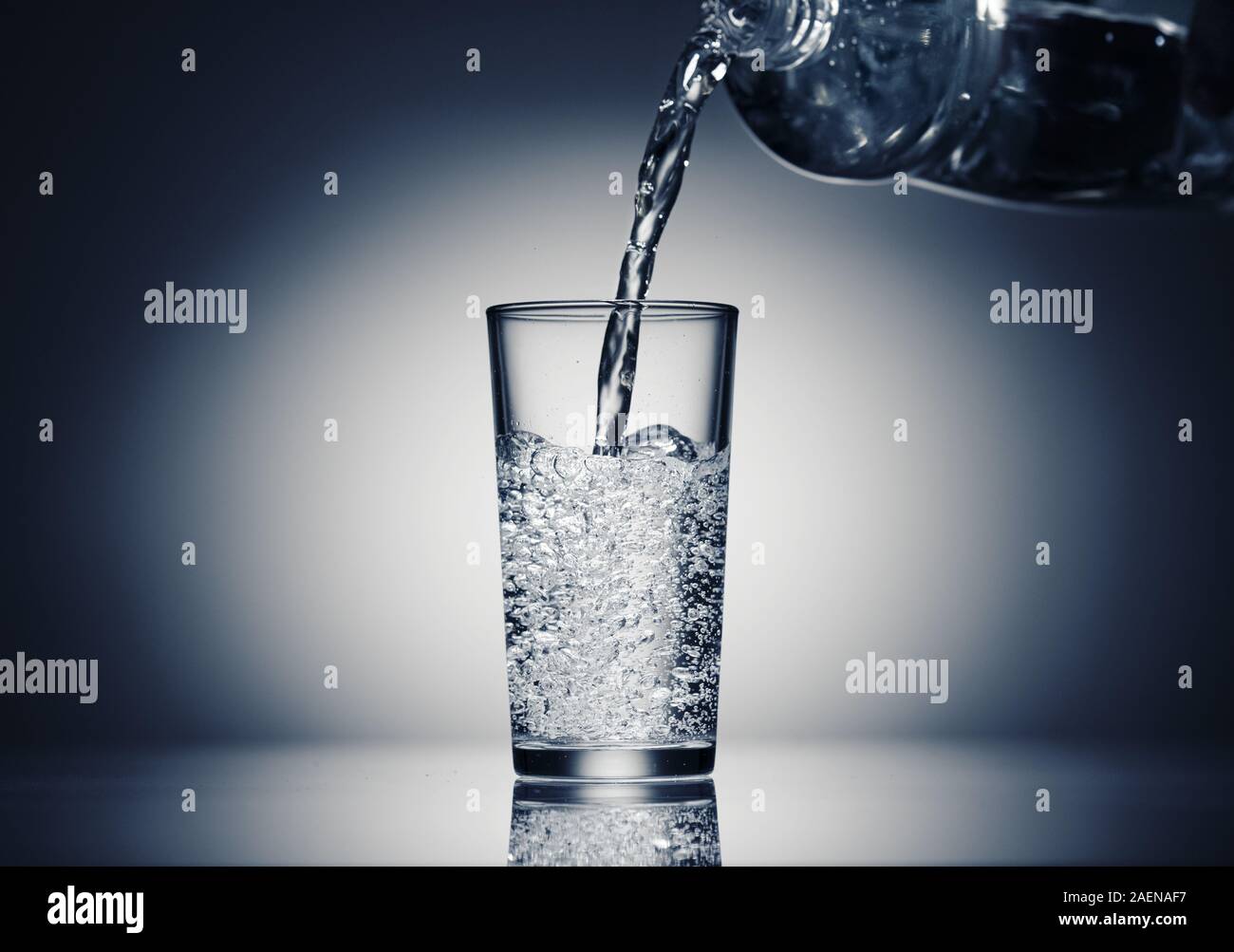 pouring sparkling water in a glass on a dark blue background Stock Photo - Alamy