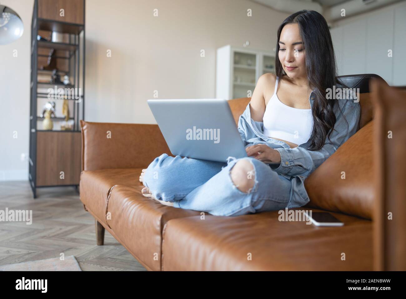 Serious woman sitting on a leather sofa Stock Photo - Alamy