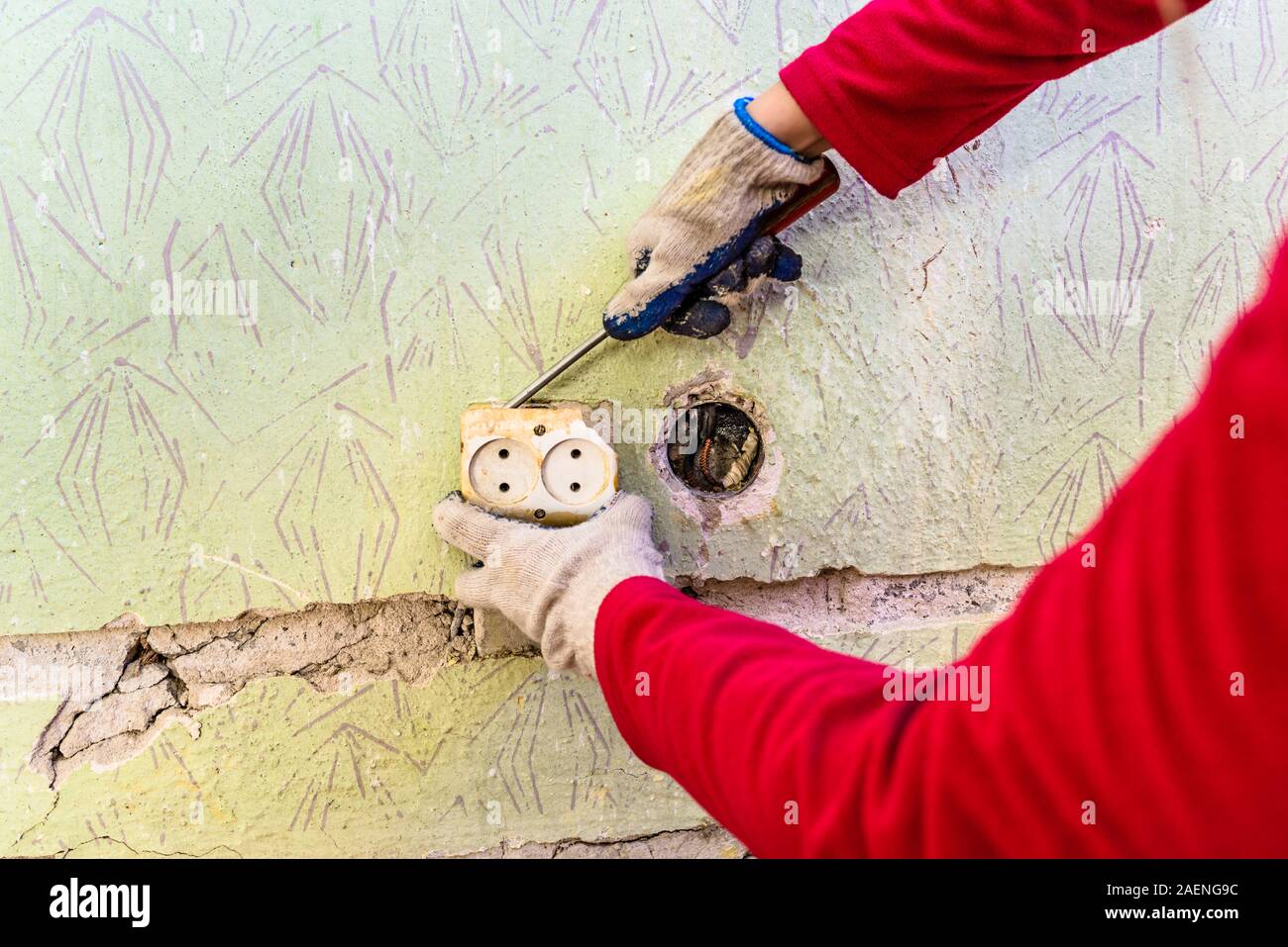 Hands of electrician repair socket on the wall. Old electrical ...