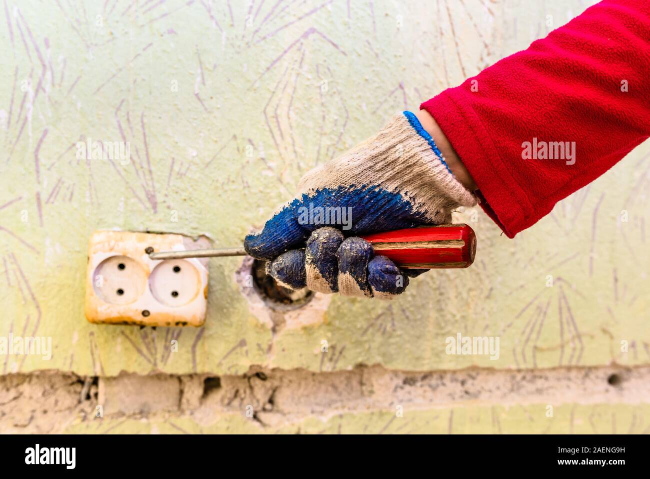 Hands of electrician repair socket on the wall. Old electrical ...