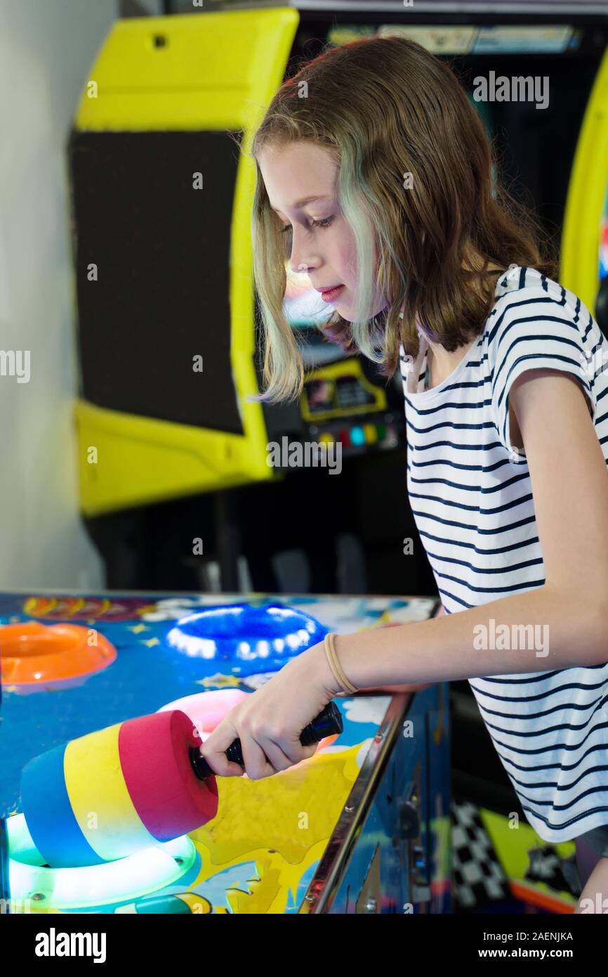 Little girl playing hammer arcade game machine in theme park Stock ...