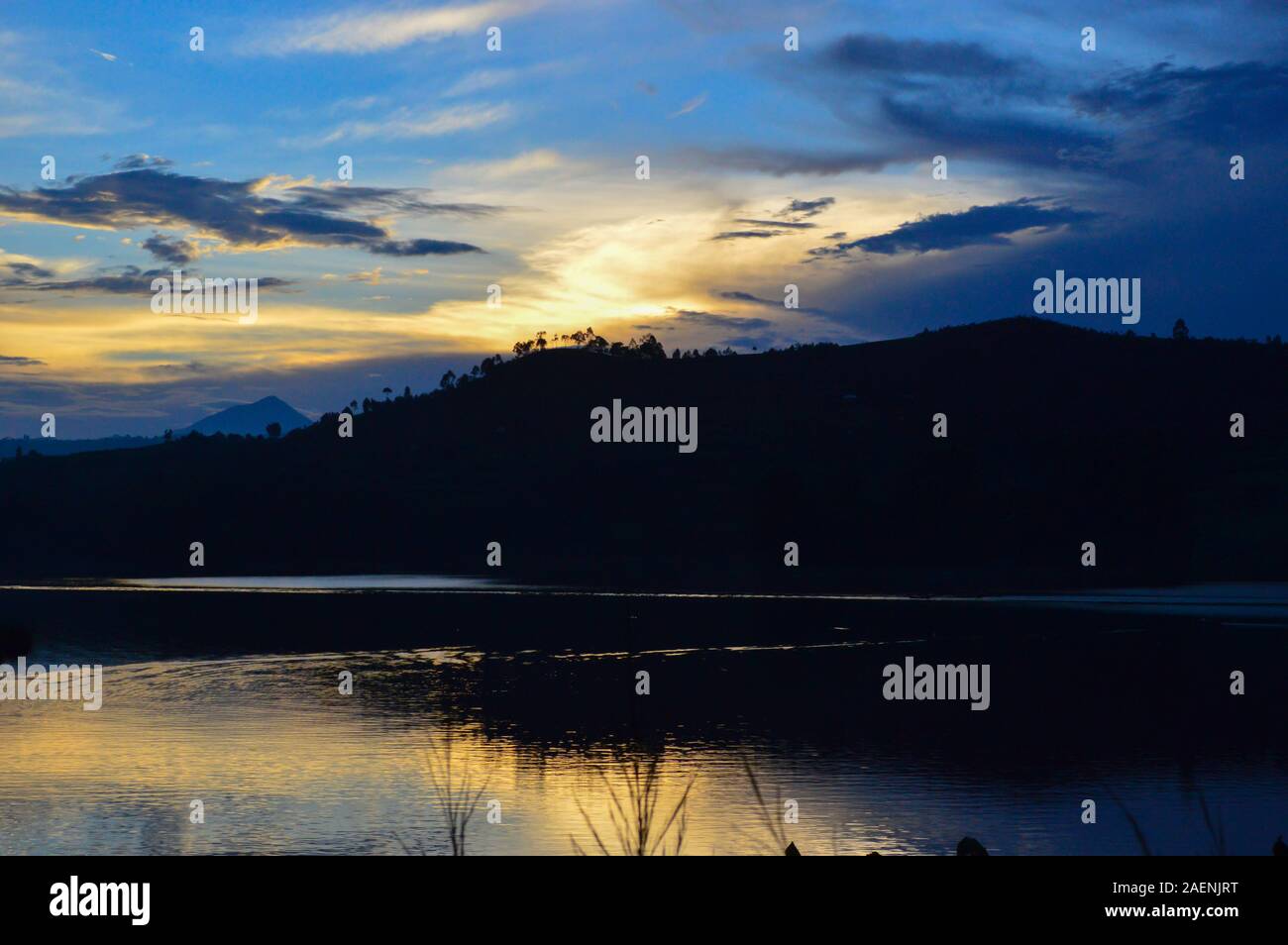 Uganda's Lake Bunyonyi after sunset. Rwanda's Muhavura volcano in the ...