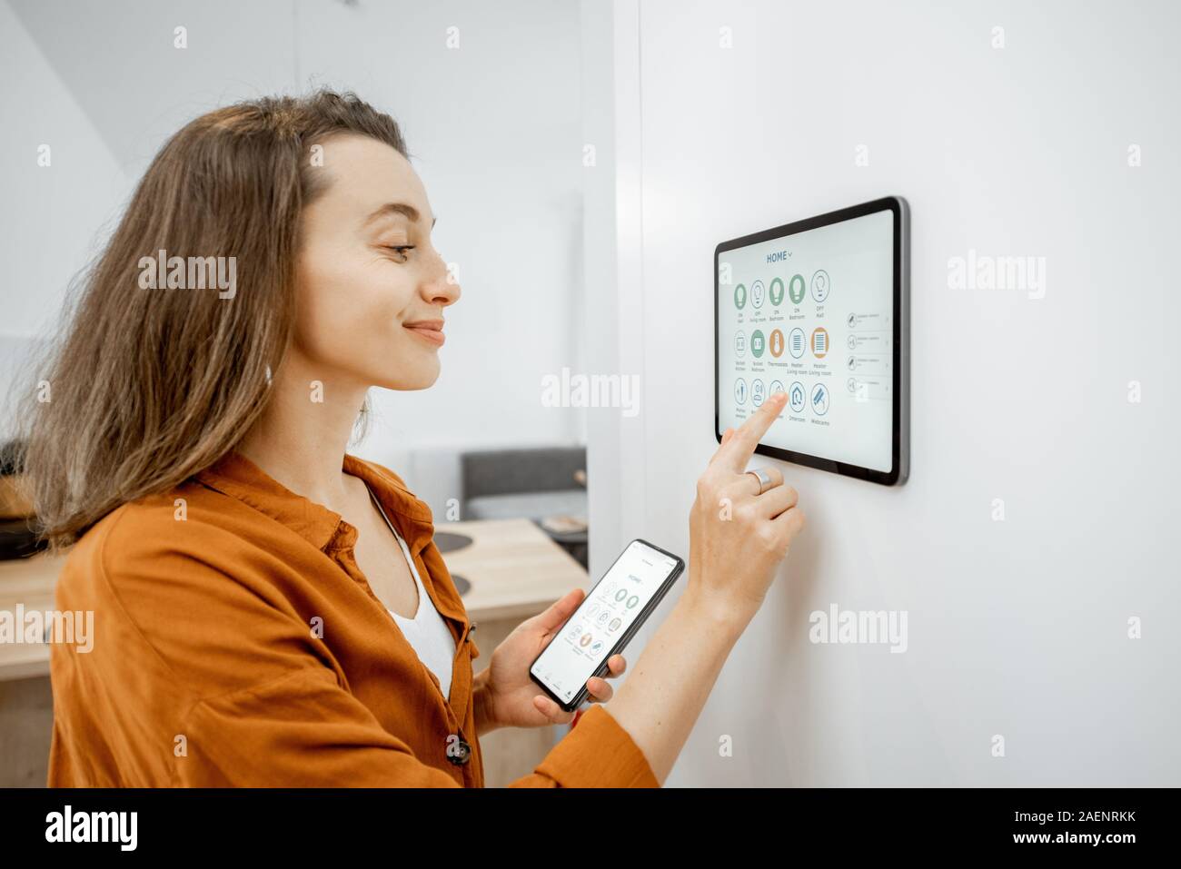 Young woman controlling home with a digital touch screen panel ...
