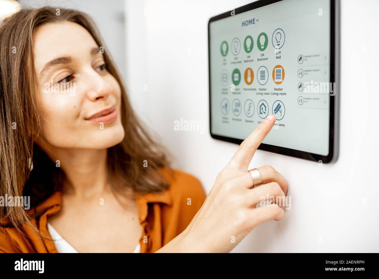 Young woman controlling home with a digital touch screen panel ...