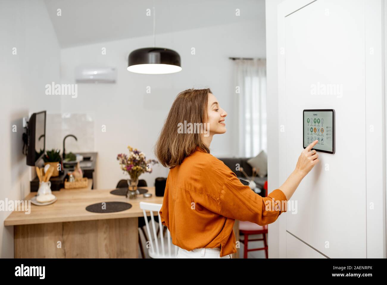 Young woman controlling home with a digital touch screen panel ...