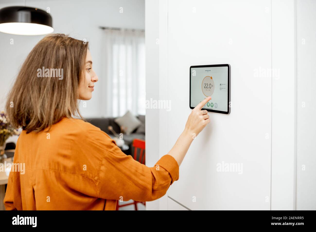Young woman controlling temperature in the living room with a digital ...
