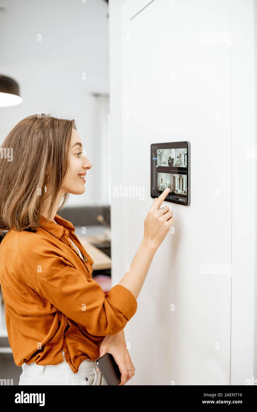Young woman watching video from security cameras on a digital tablet at ...