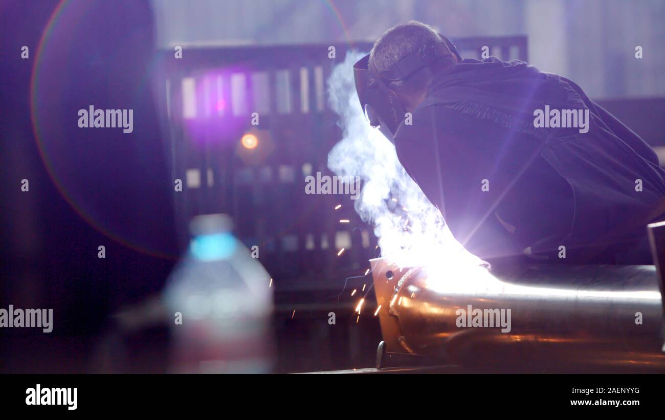 Welding fittings with electrodes. Welder in mittens and helmet with ...