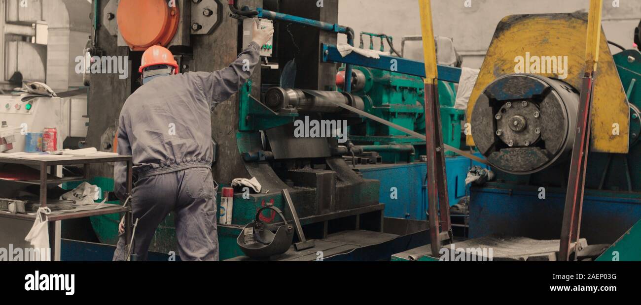 Manufacturing worker operating machine with a control panel in metal ...