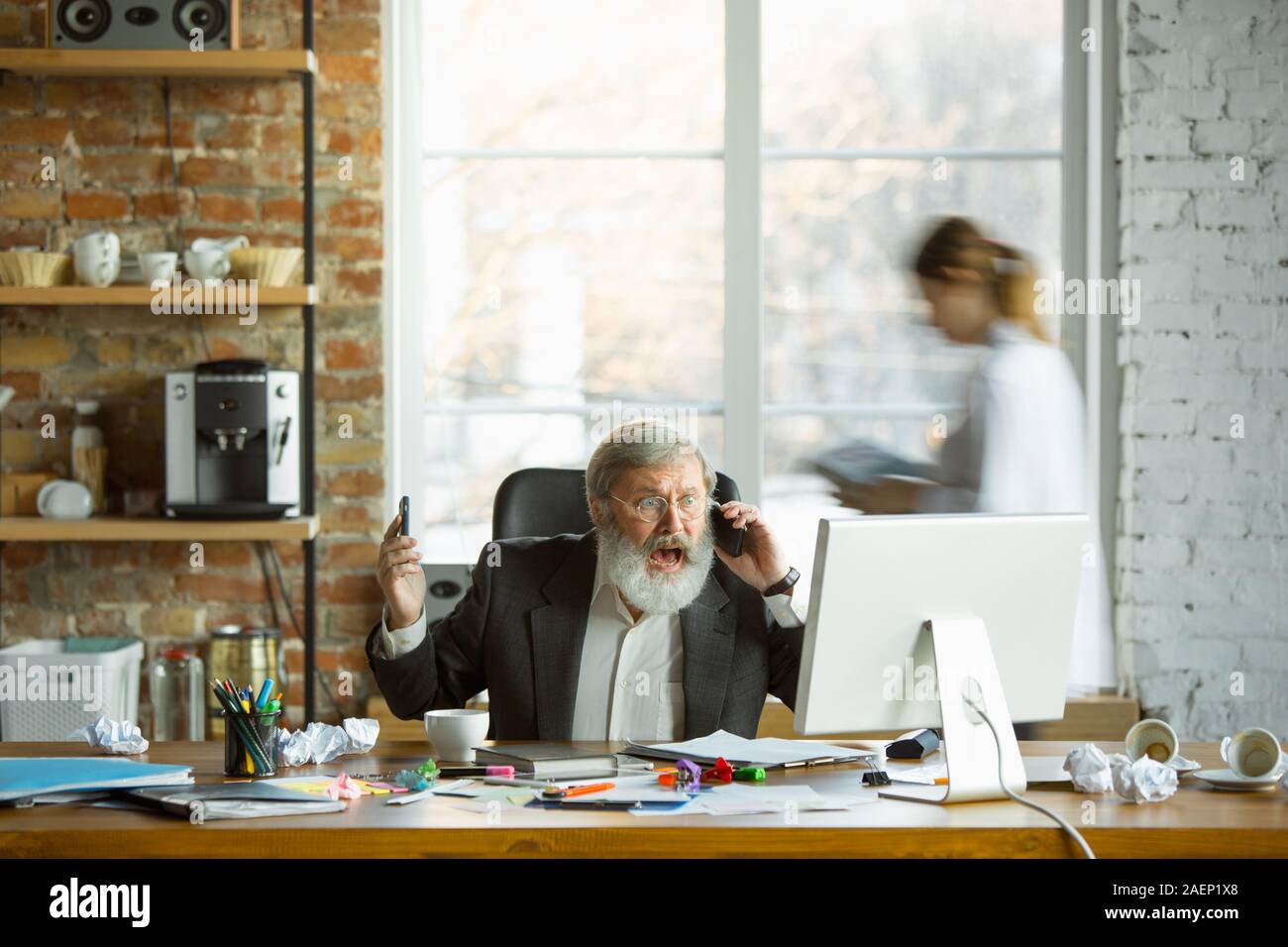 Nervous and tired boss at his workplace busy while people moving near ...