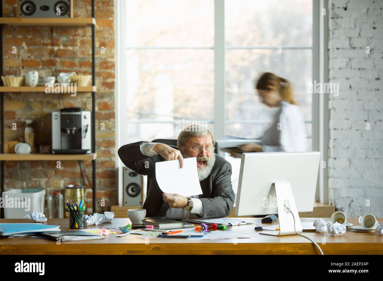 Nervous and tired boss at his workplace busy while people moving near ...